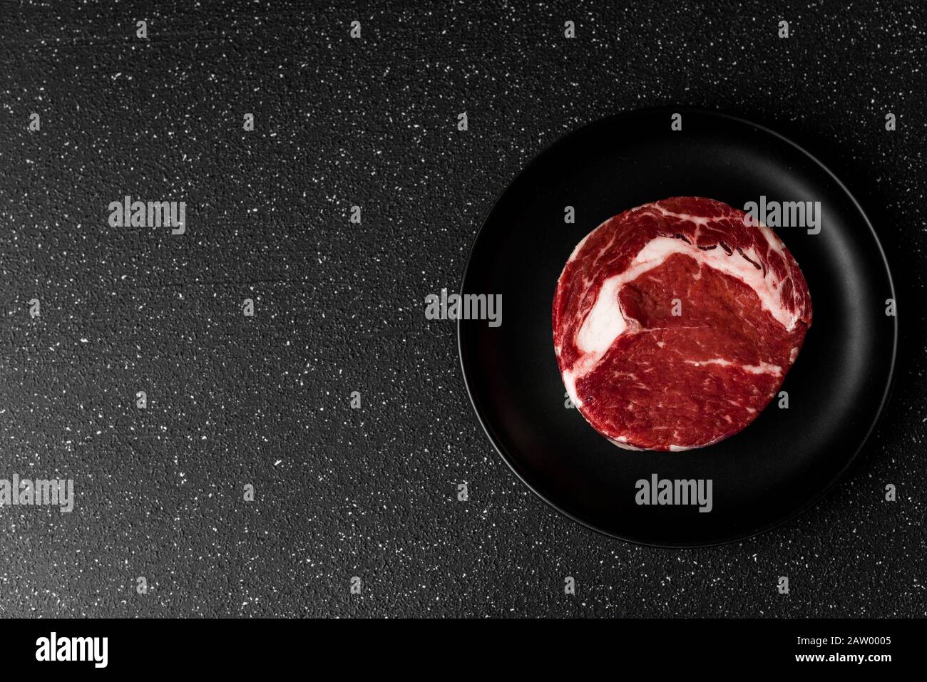 Raw prime beef rib eye meat food steak against black stone background ...
