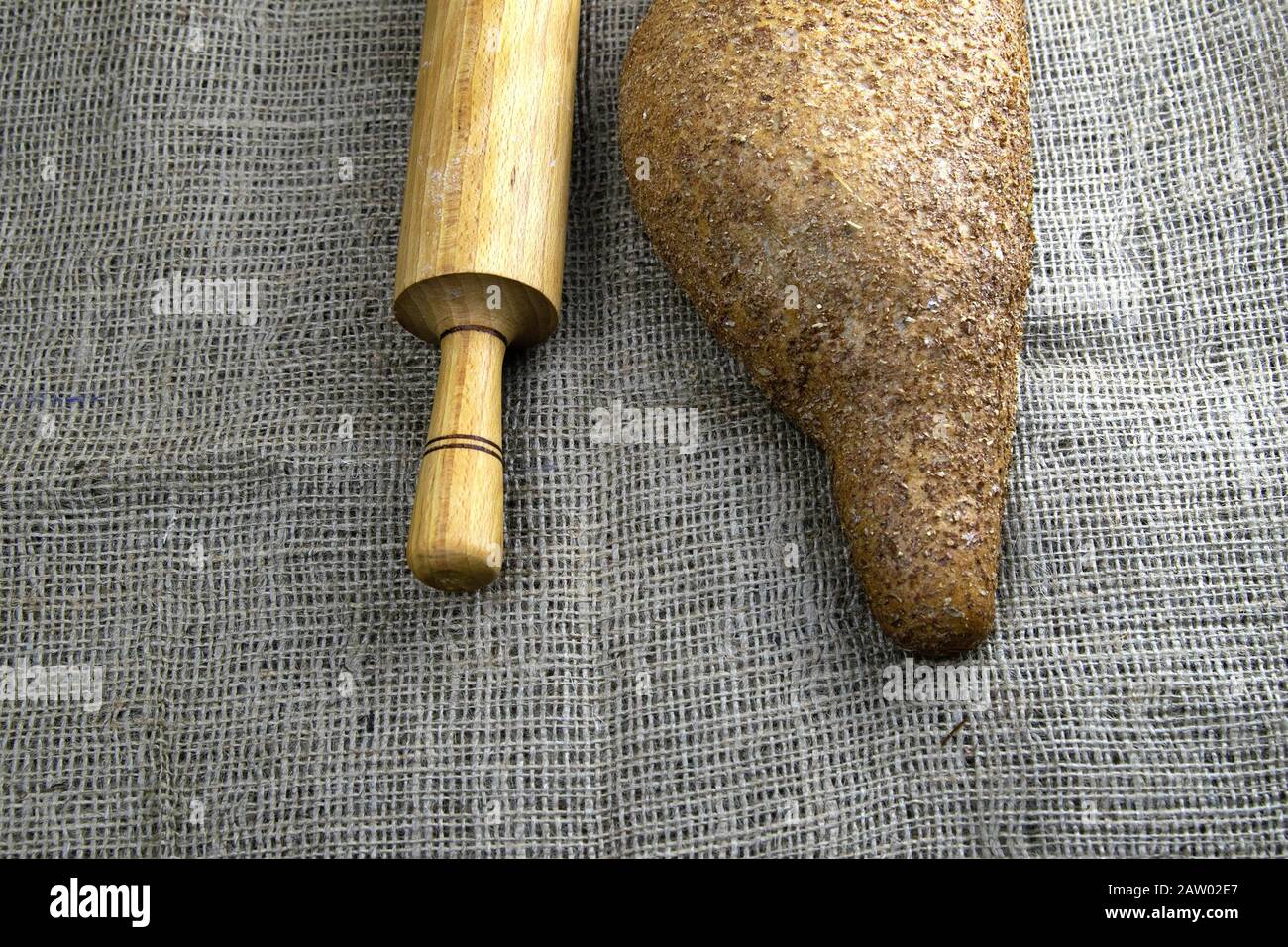A loaf of bread with a rolling pin for dough stand on a craft linen bag ...