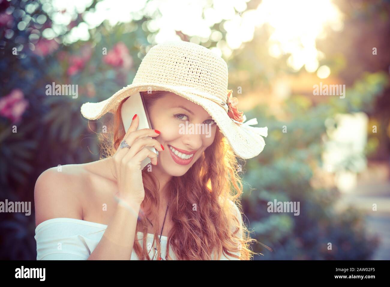 Happy at mobile phone. Euphoric woman in straw hat talking to her smart ...