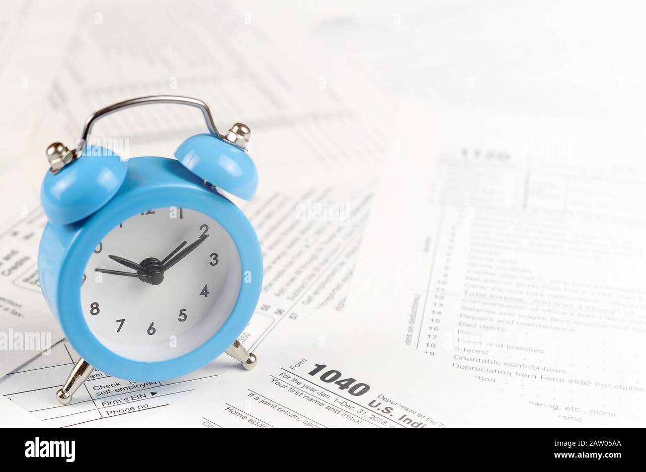 1040 Individual income tax return form with blue alarm clock. Concept ...