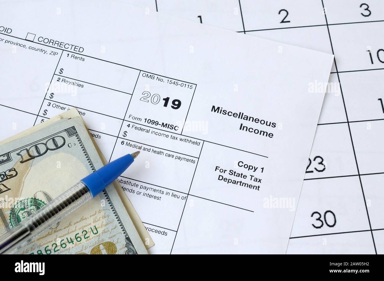 Form 1099-misc Miscellaneous income and blue pen with dollar bills lies ...