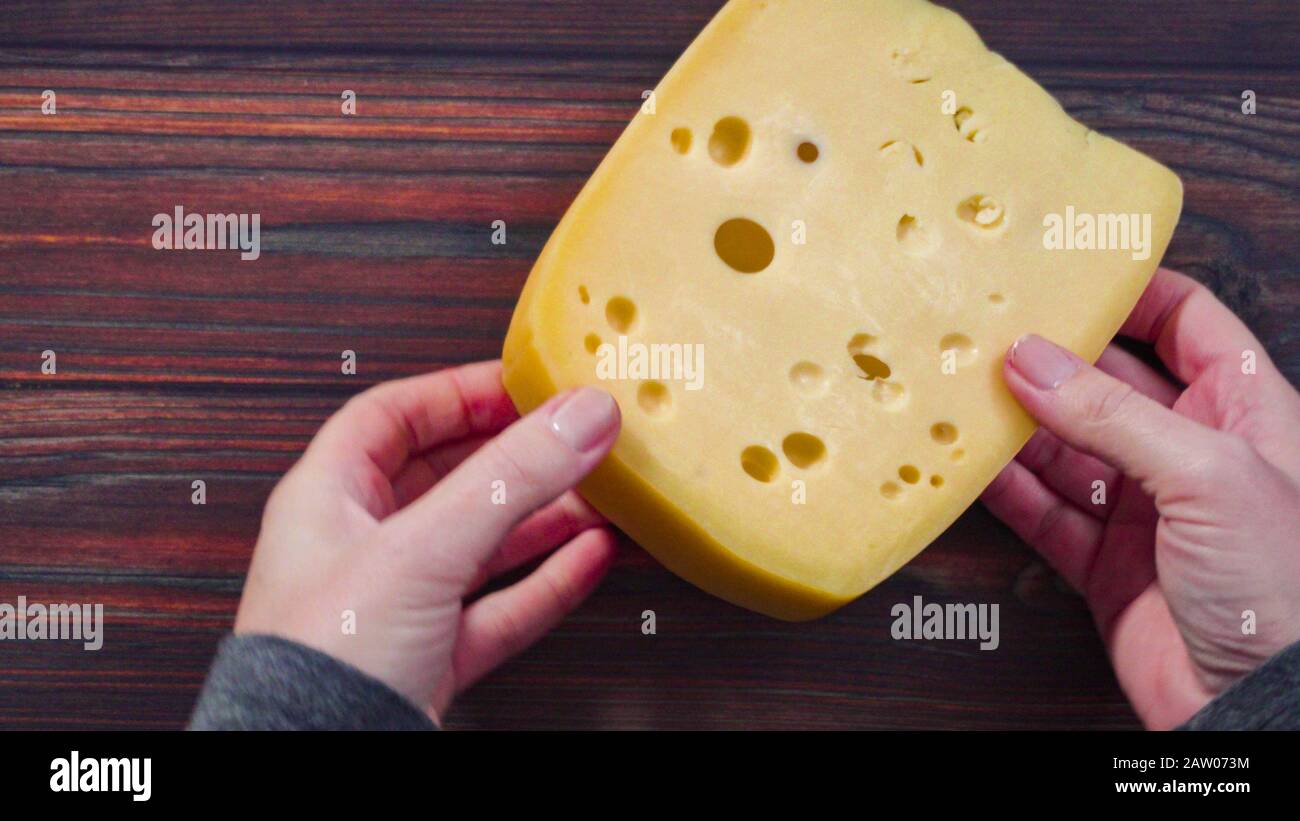 Flat lay. Large wedge of semi-soft part skim cheese on a rustic wood ...