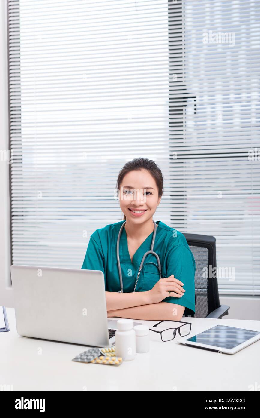 Female doctor working at office desk and smiling at camera, office ...