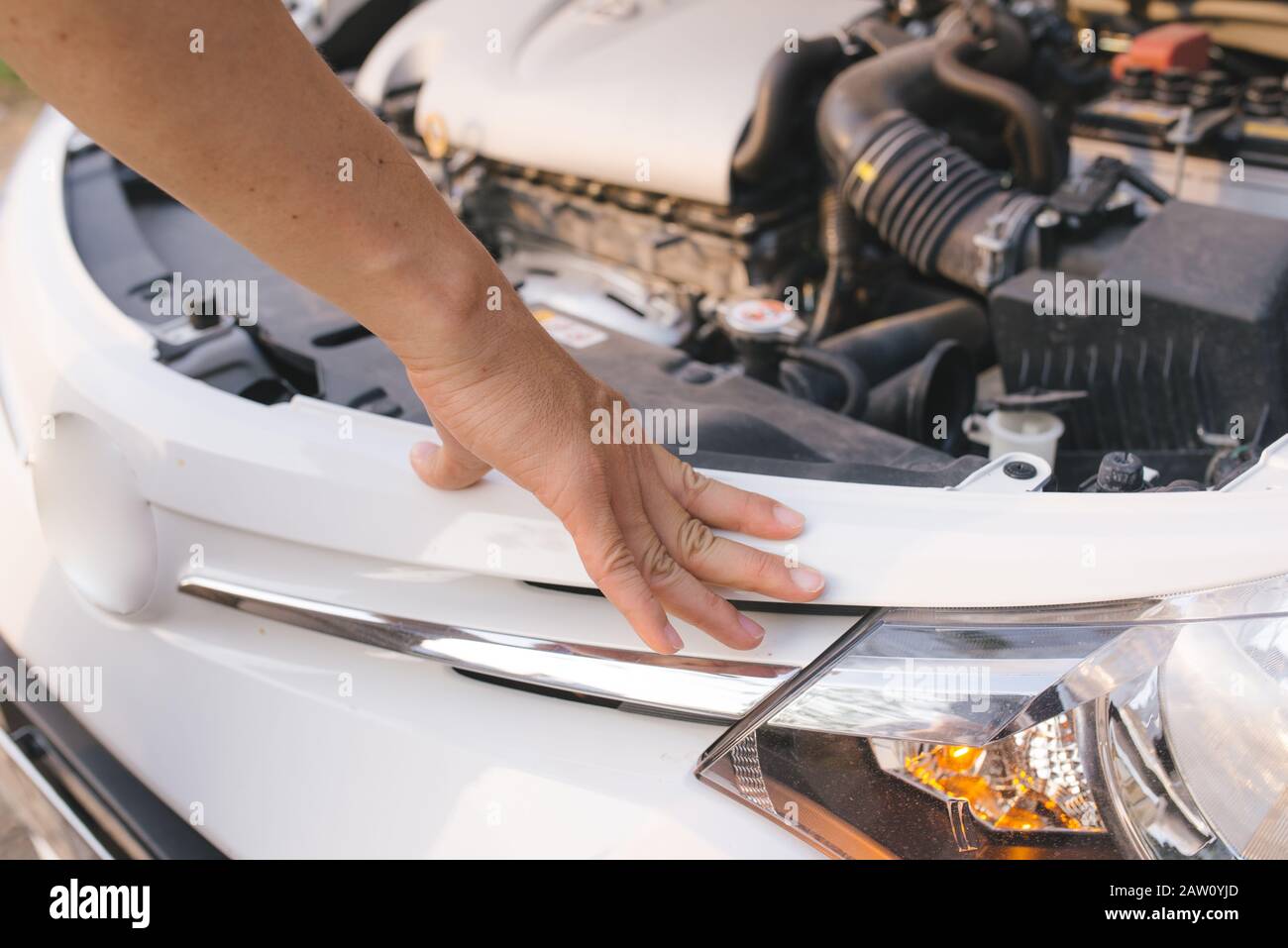 young stressed man having trouble with his broken car looking in ...
