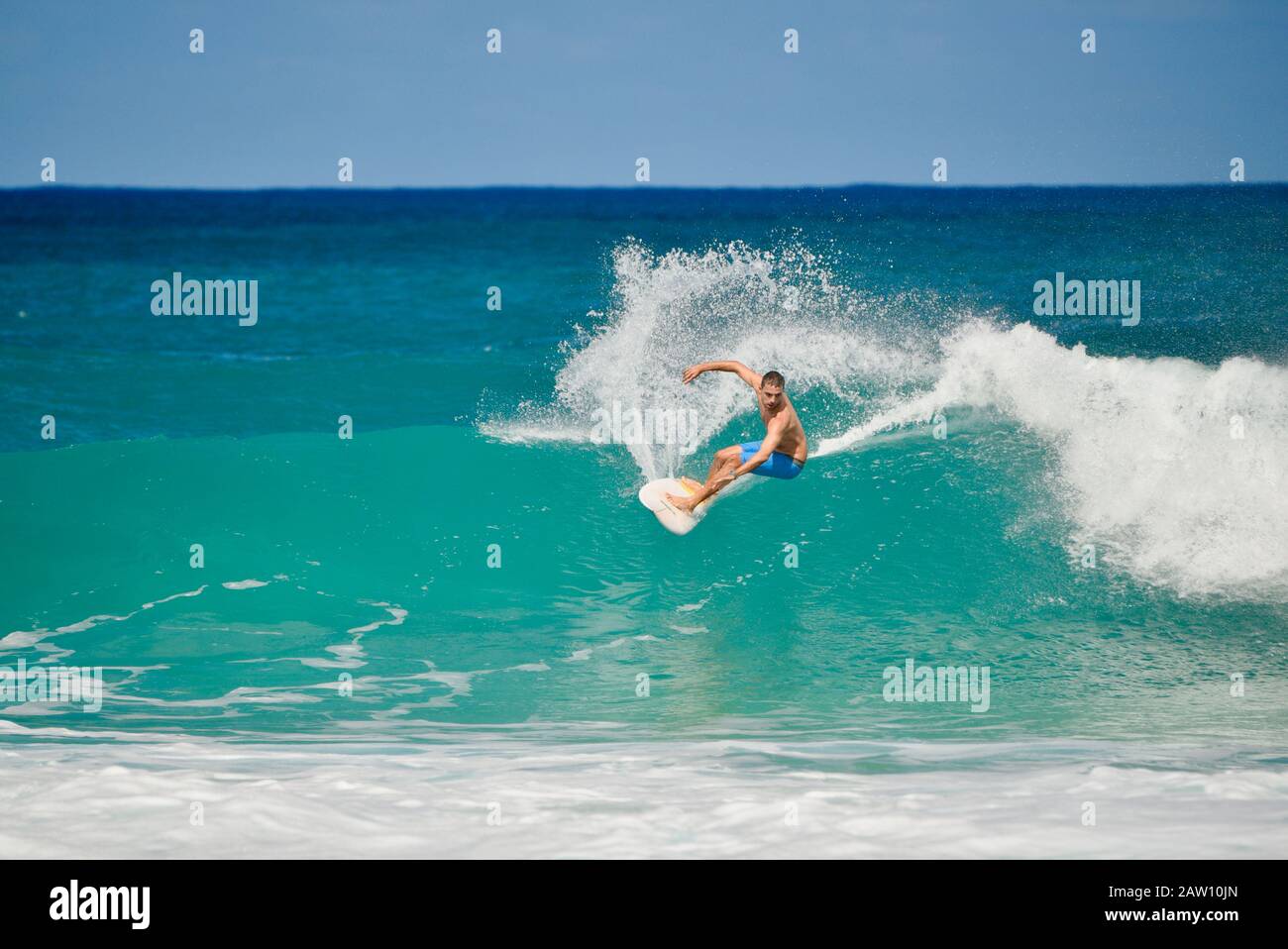 Surfer riding world-renowned crashing, barreling curved turquoise waves ...