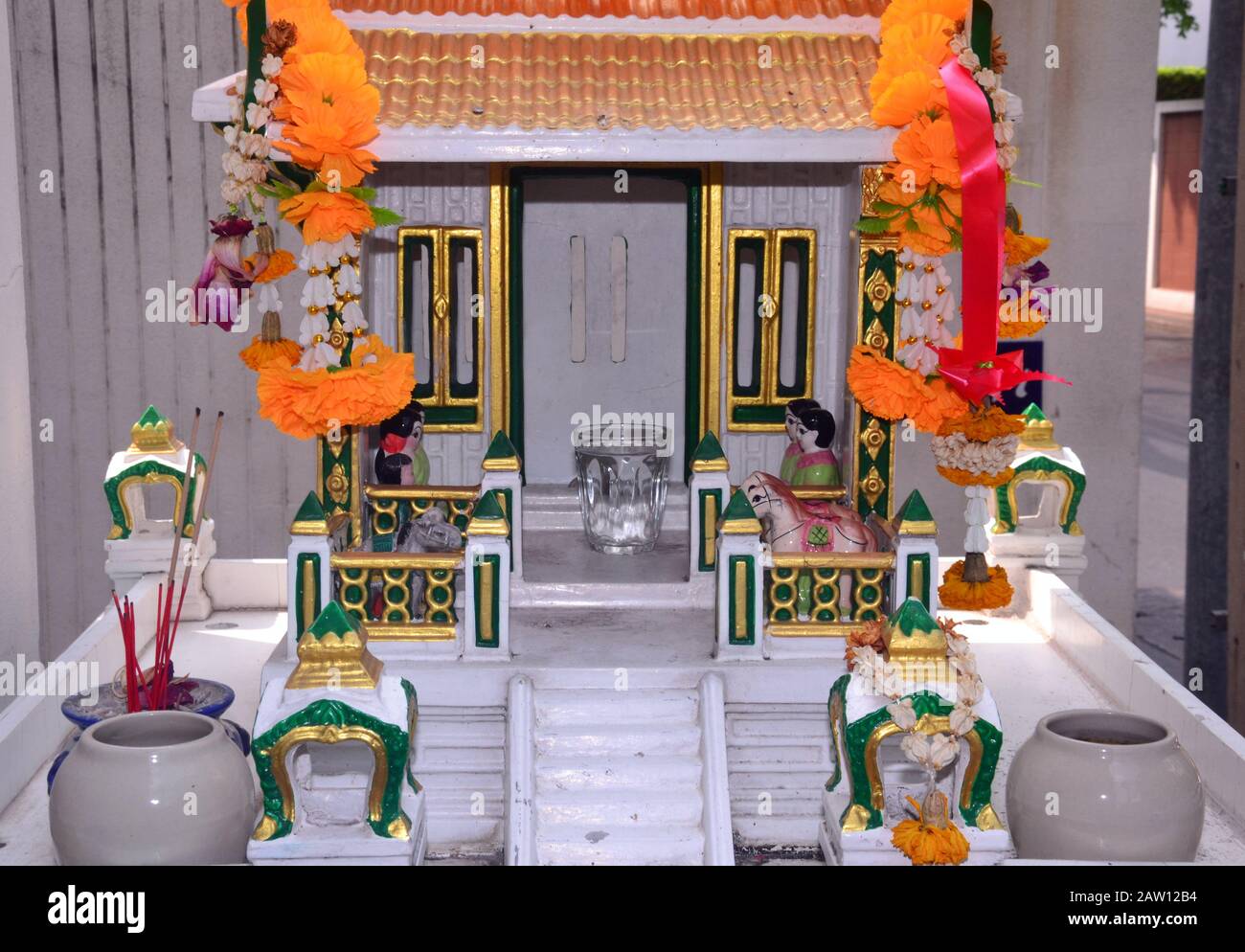 Offerings on a typical Thai spirit house or religious shrine, whose aim ...