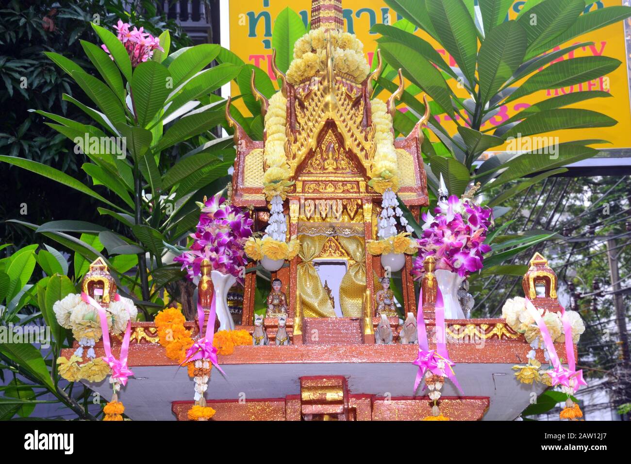 Offerings on a typical Thai spirit house or religious shrine, whose aim ...