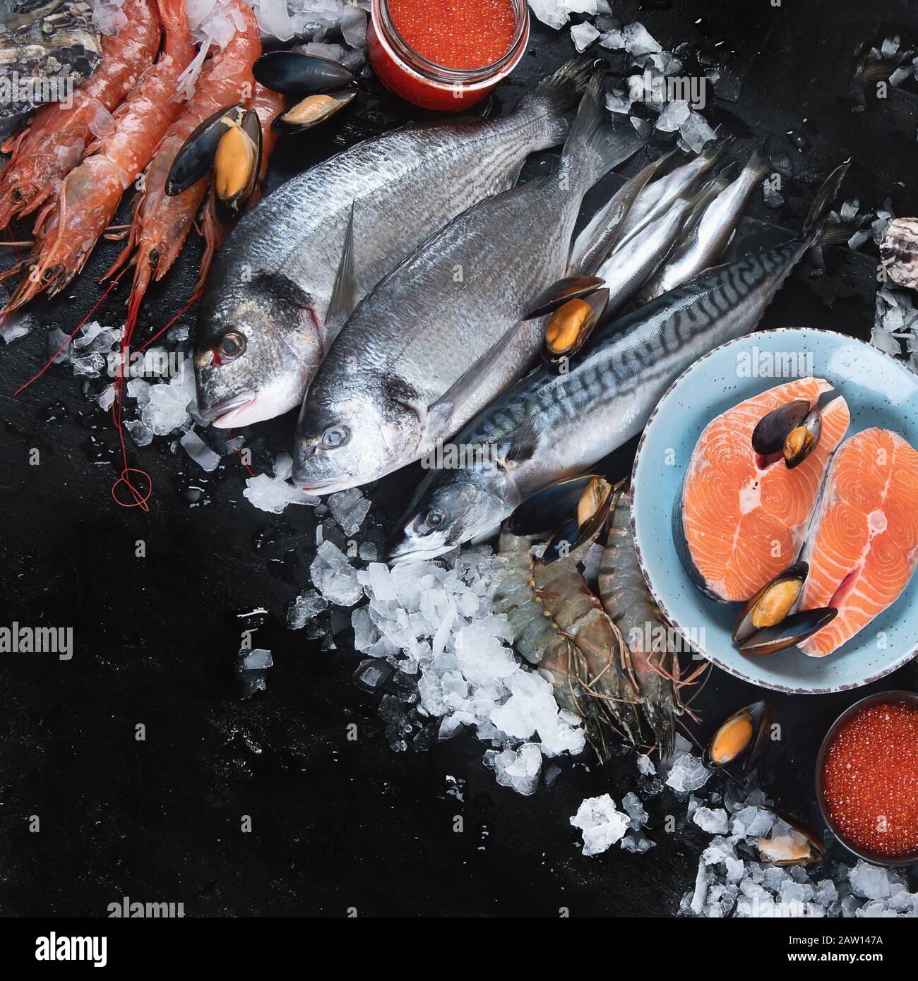 Fresh fish and seafood on black background. Top view with copy space ...