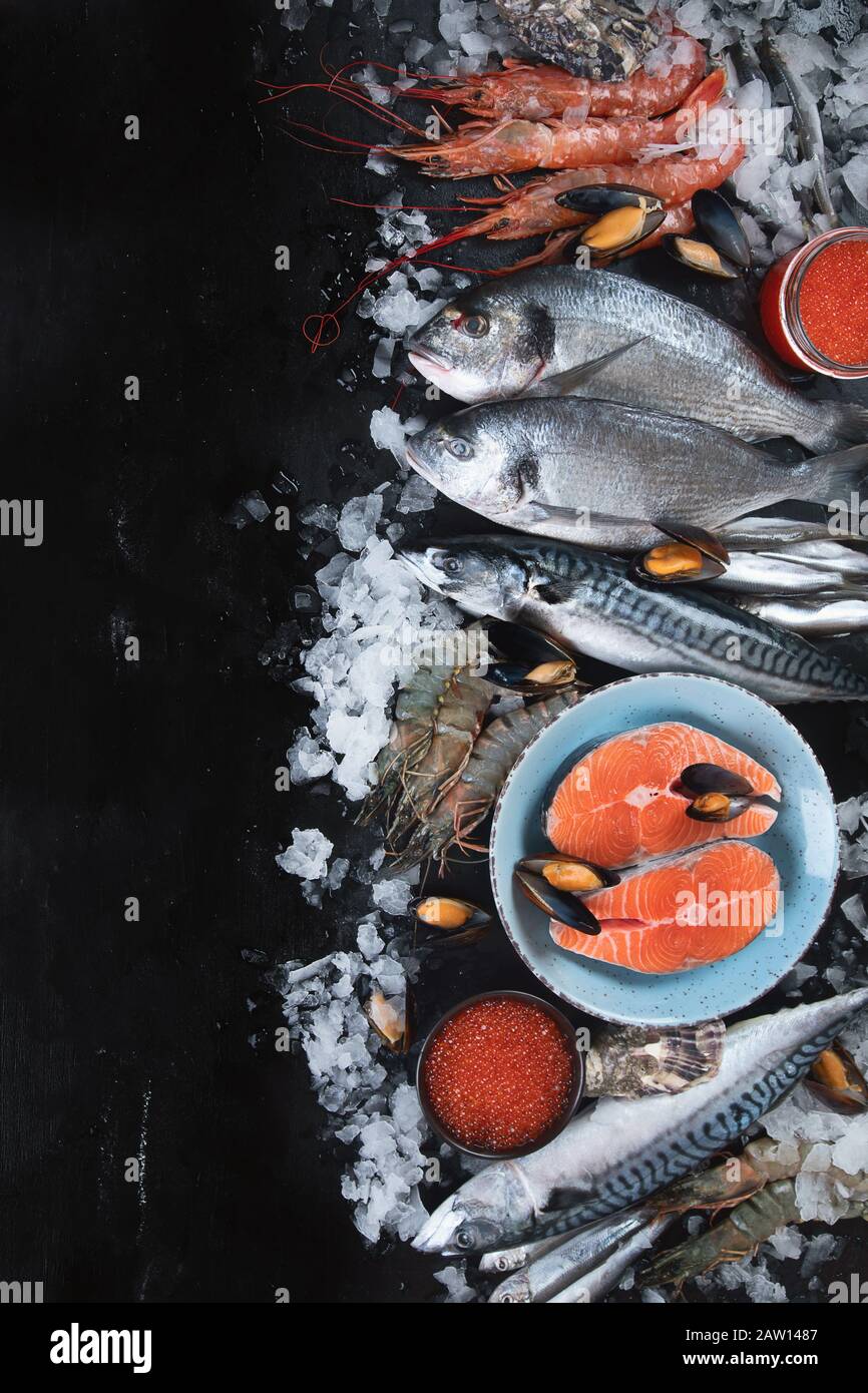 Fresh fish and seafood on black background. Top view with copy space ...