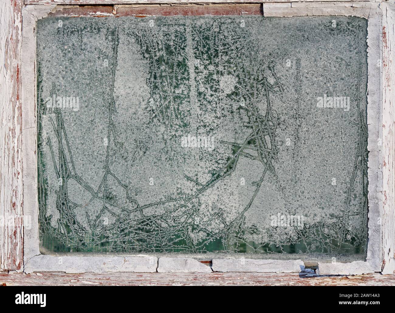 A worn out window with frost made figures on the glass surface Stock ...