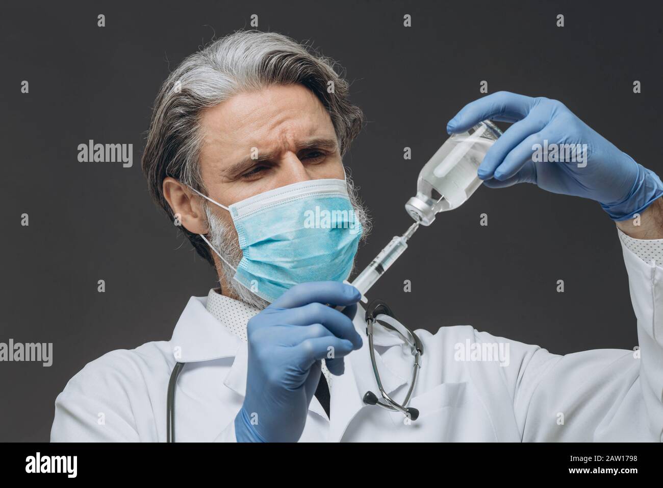 Old serious doctor holding syringe with vaccine. Ready to make ...