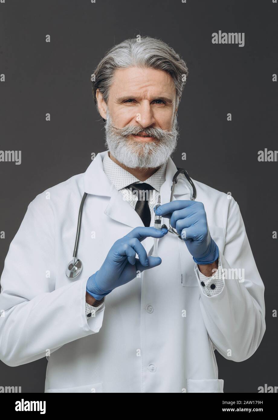 Old serious doctor holding syringe with vaccine. Ready to make ...