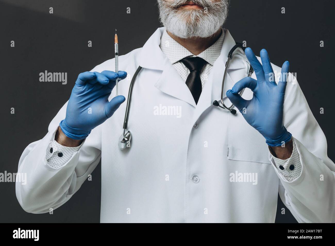 Old serious doctor holding syringe with vaccine. Ready to make ...