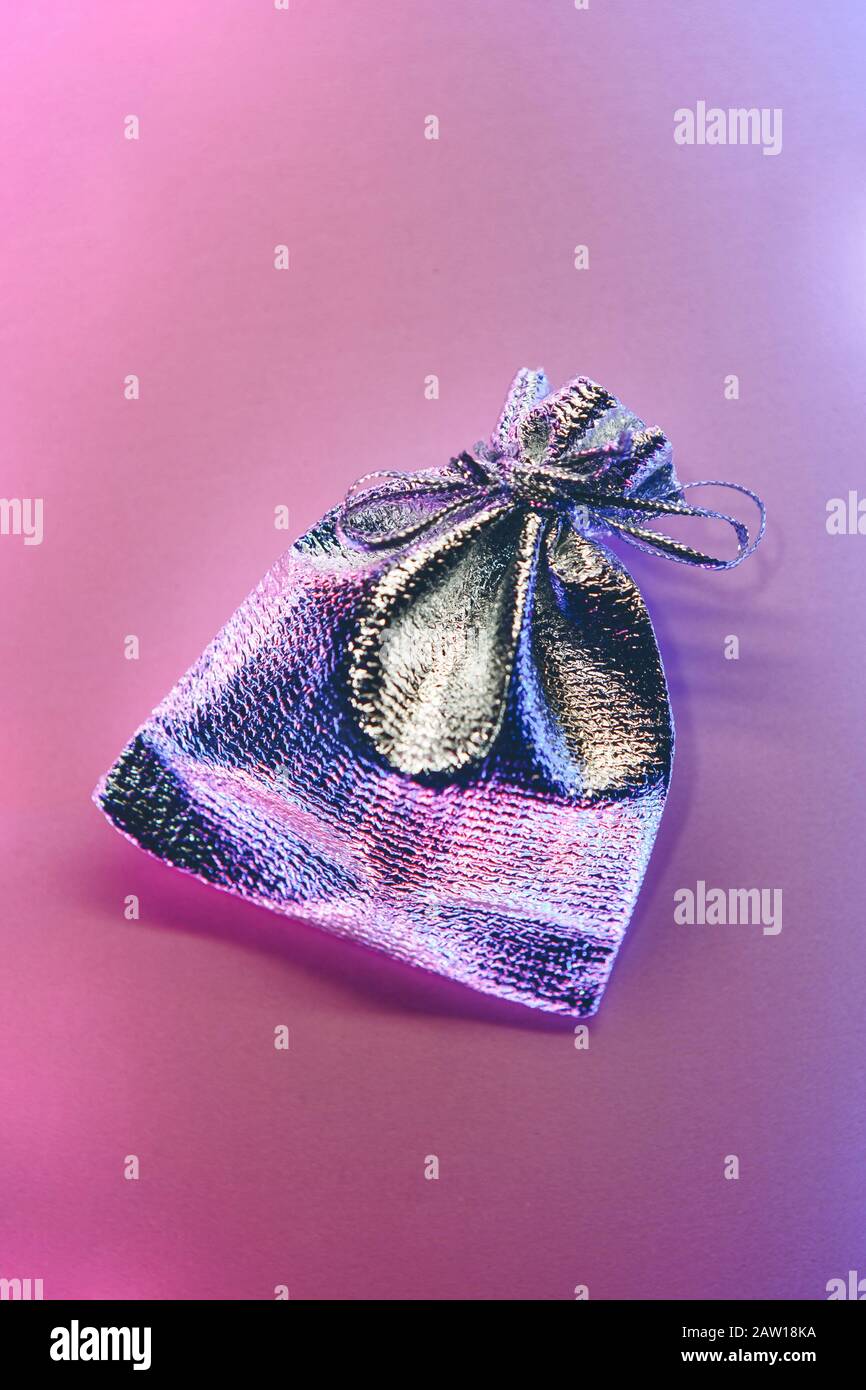 Silver small gift bag on a gradient background illuminated by neon ...