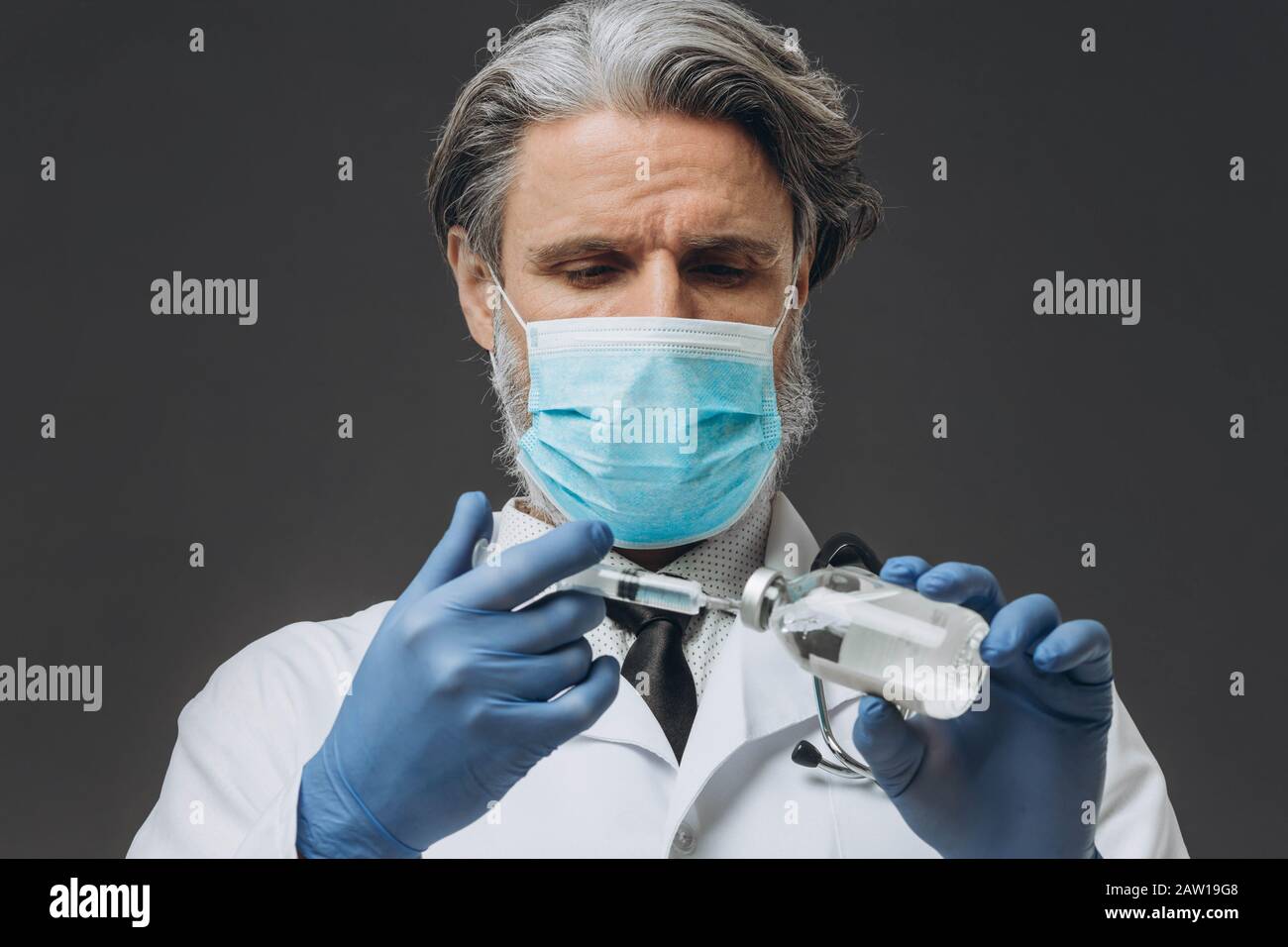 Old serious doctor holding syringe with vaccine. Ready to make ...