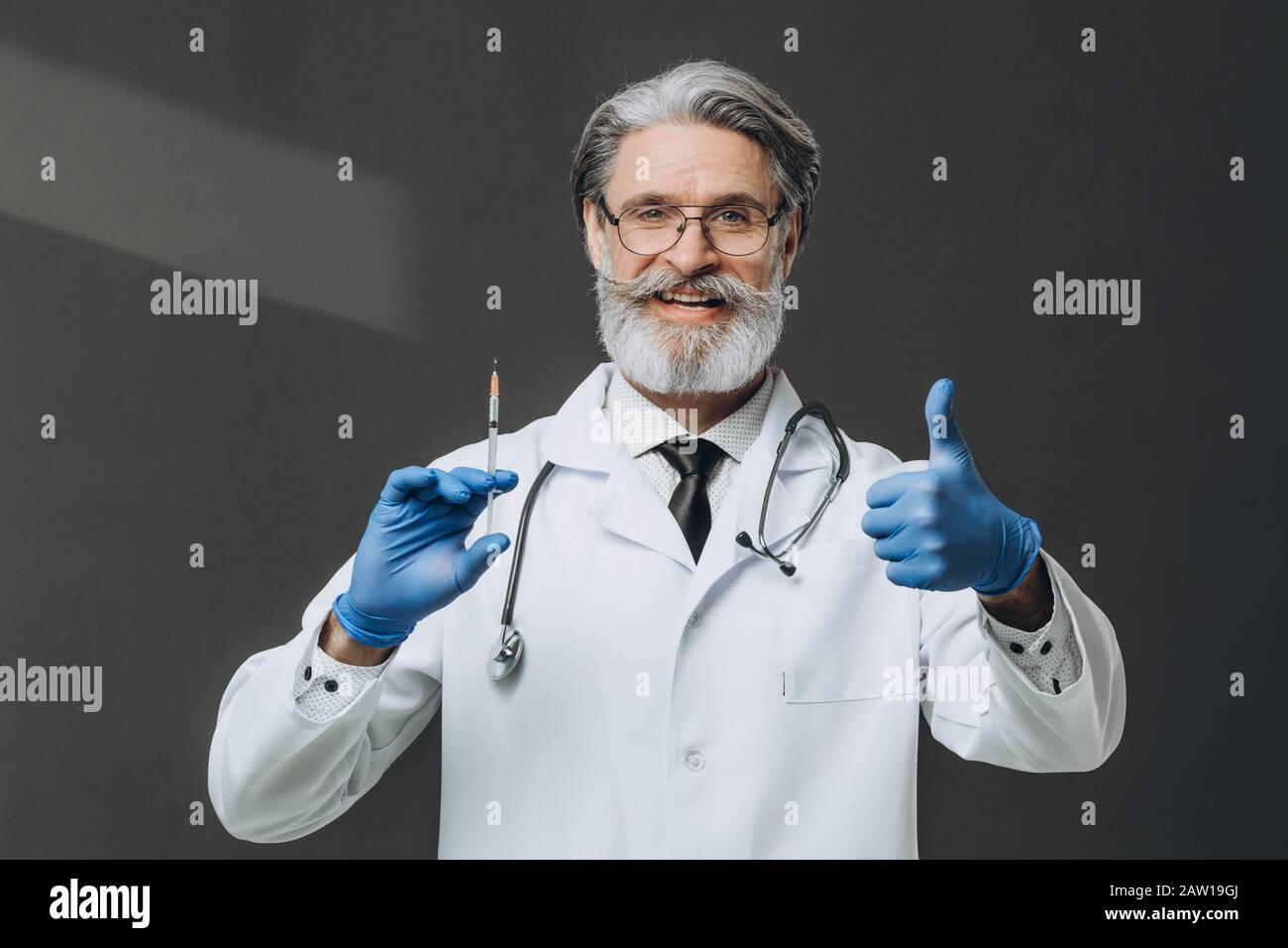 Old serious doctor holding syringe with vaccine. Ready to make ...