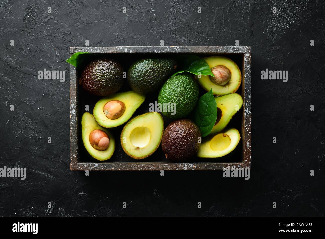 Avocado with leaves in the box. Rustic style. Top view. Free space for ...