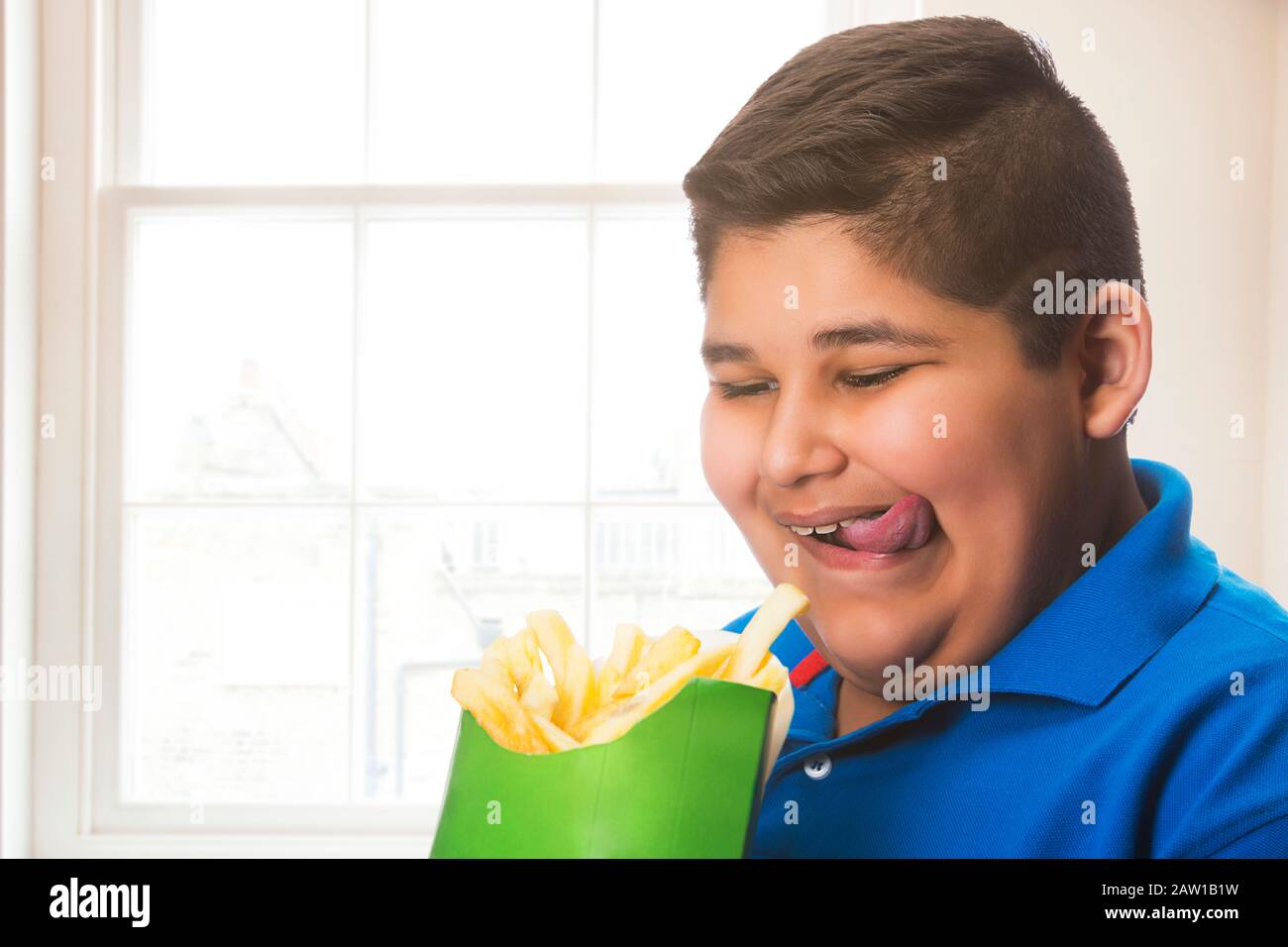 Young boy hungrily looking at fries. (Obesity Stock Photo - Alamy