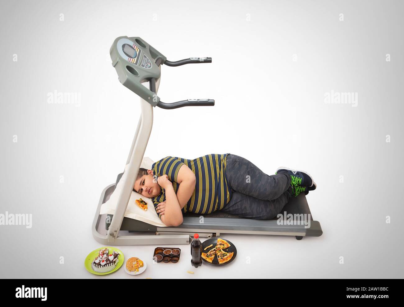 Young boy sleeping on the treadmill with lots of junk food around him ...