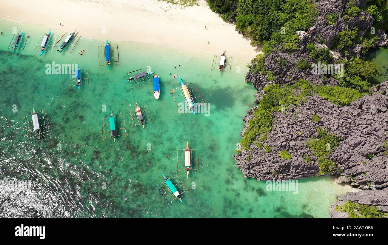 Sandy beach with tourists and tropical island by atoll with coral reef ...