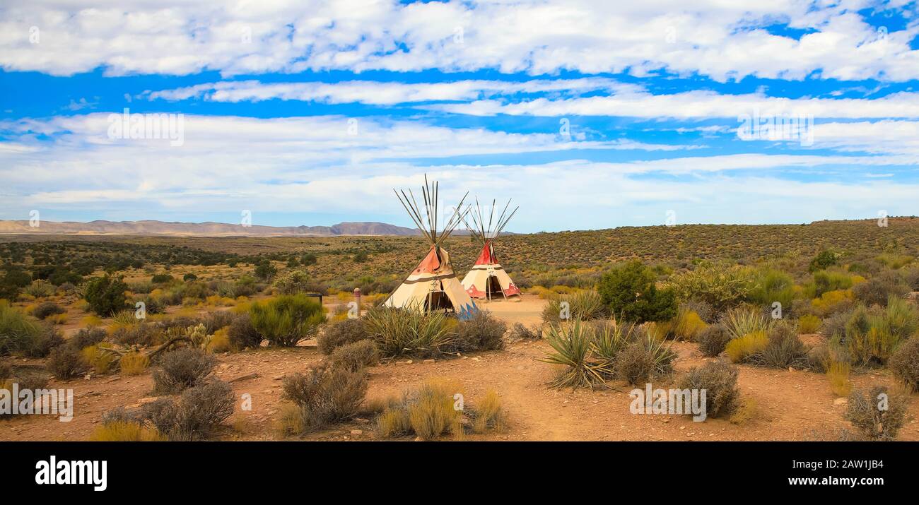 Two teepees which are Native American tents, stand on a grassy hill in ...