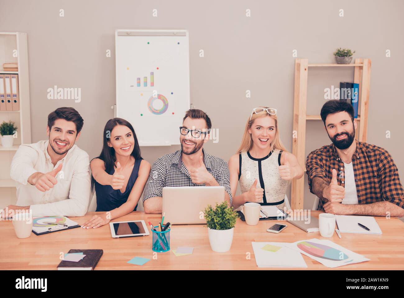 photo of happy young team sitting at conference table smiling and thumb ...