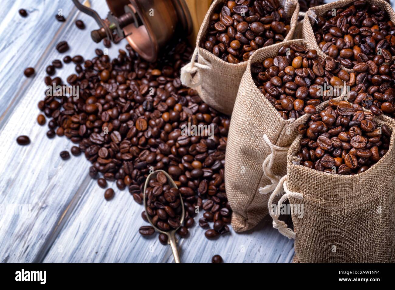 Coffee seeds in spoon with some jute bags filled with coffee and coffee ...