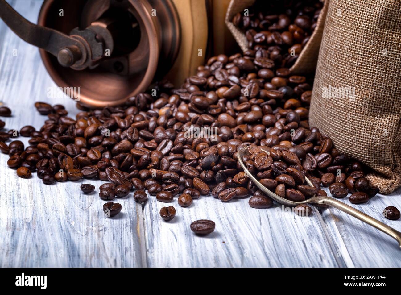 Coffee seeds in spoon with some jute bags filled with coffee and coffee ...