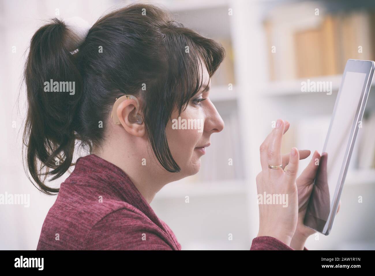 Deaf woman wearing hearing aid and using tablet Stock Photo - Alamy