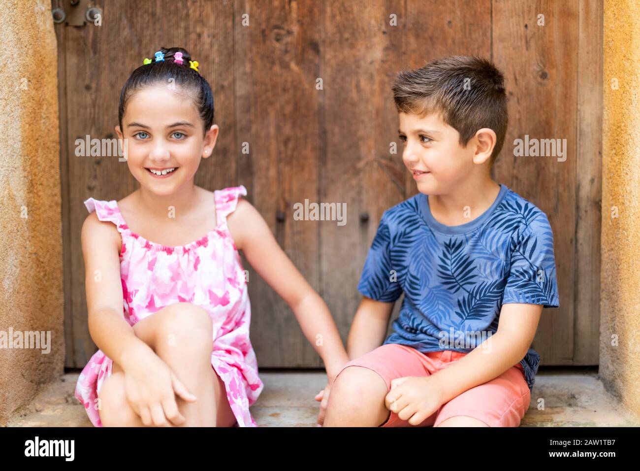 Portrait of two children sitting holding hands Stock Photo - Alamy