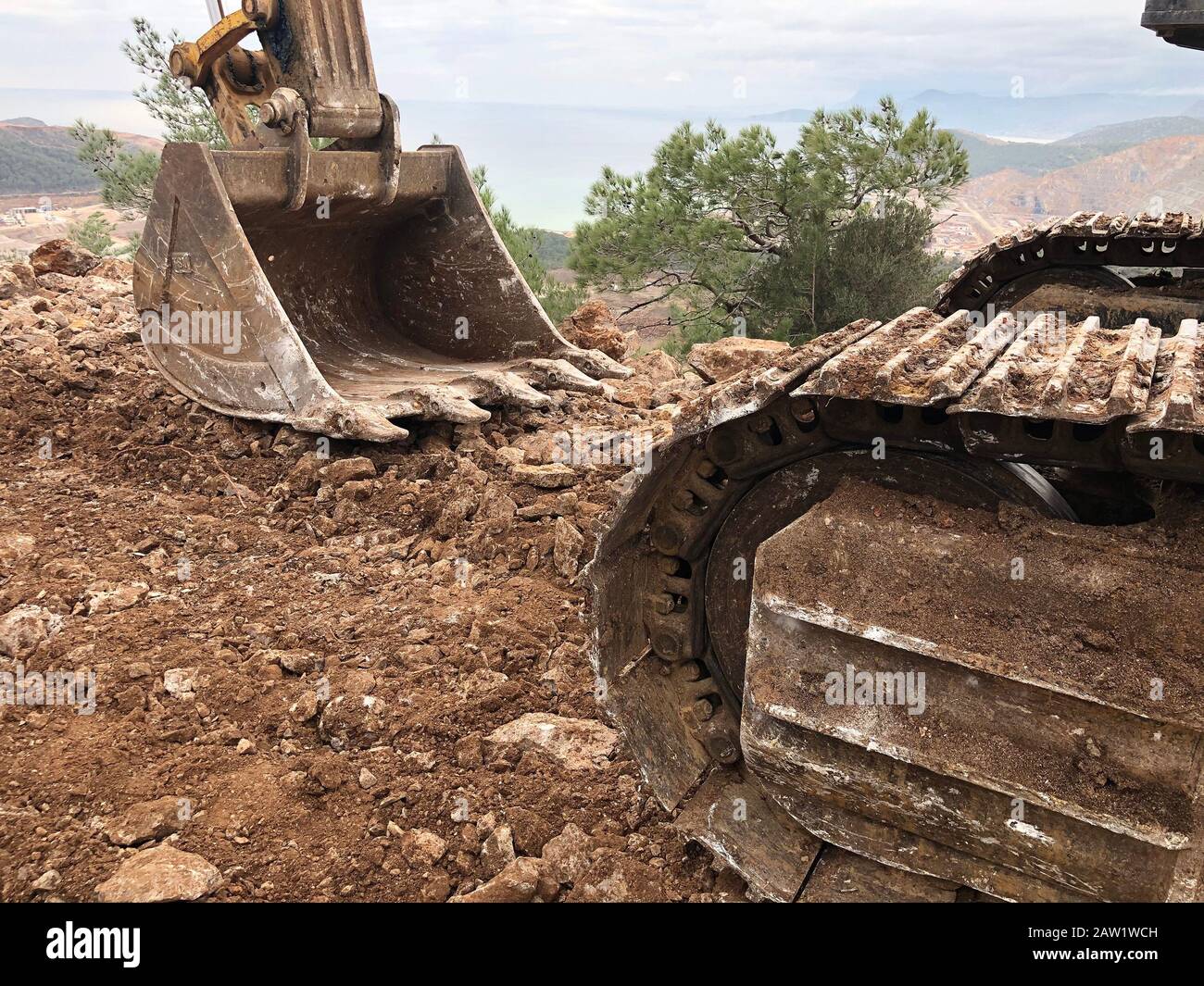 Excavator scoop flattens soil during road construction on the rocky ...