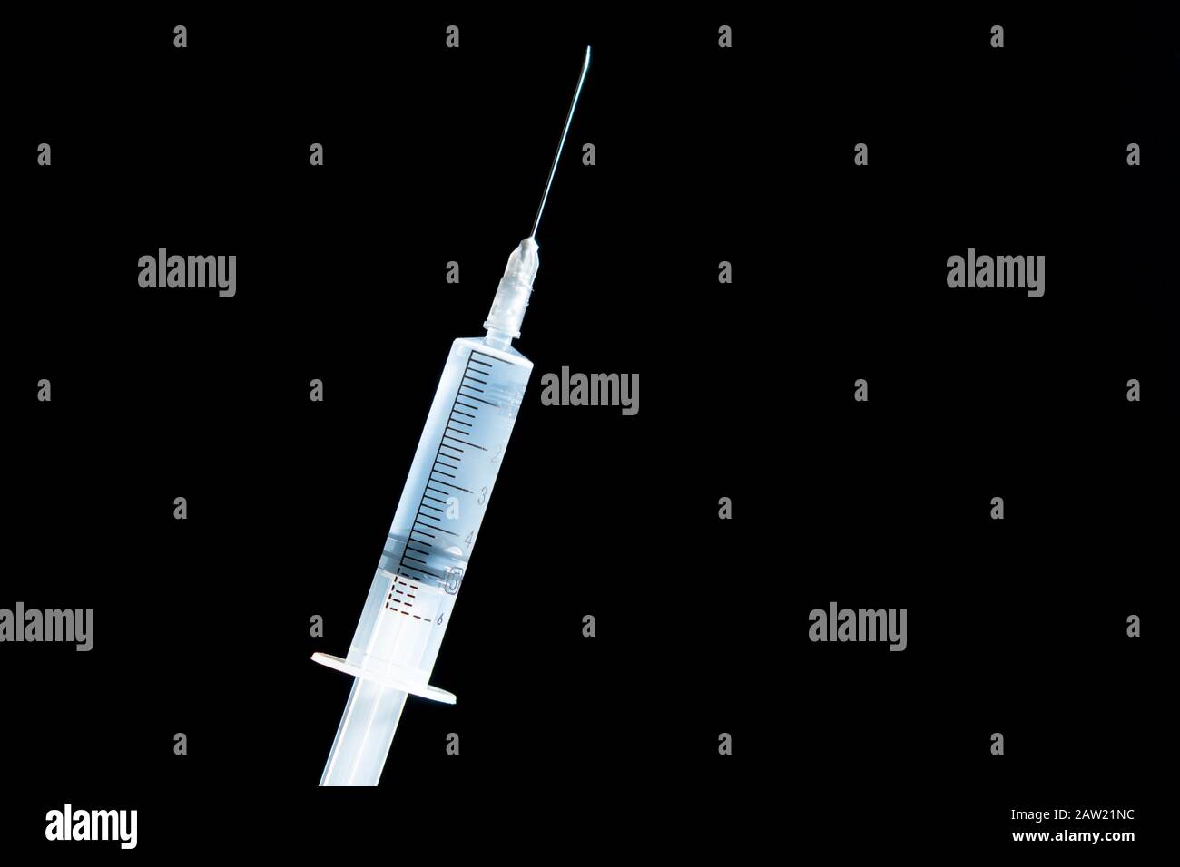 Disposable medical syringe with liquid on a black background. Close-up ...