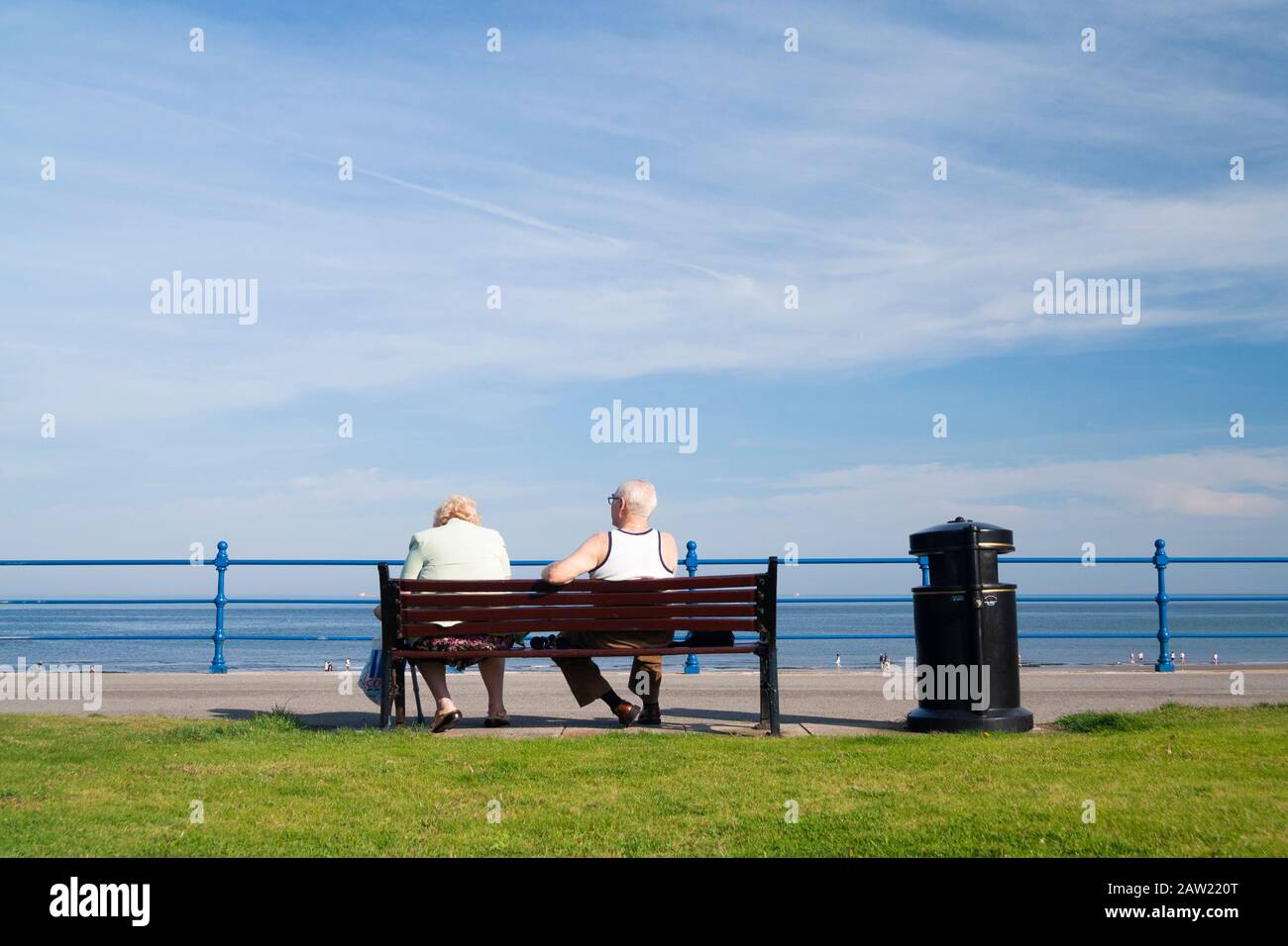 Rear view of elderly couple sitting on seat overlooking beach. UK Stock ...