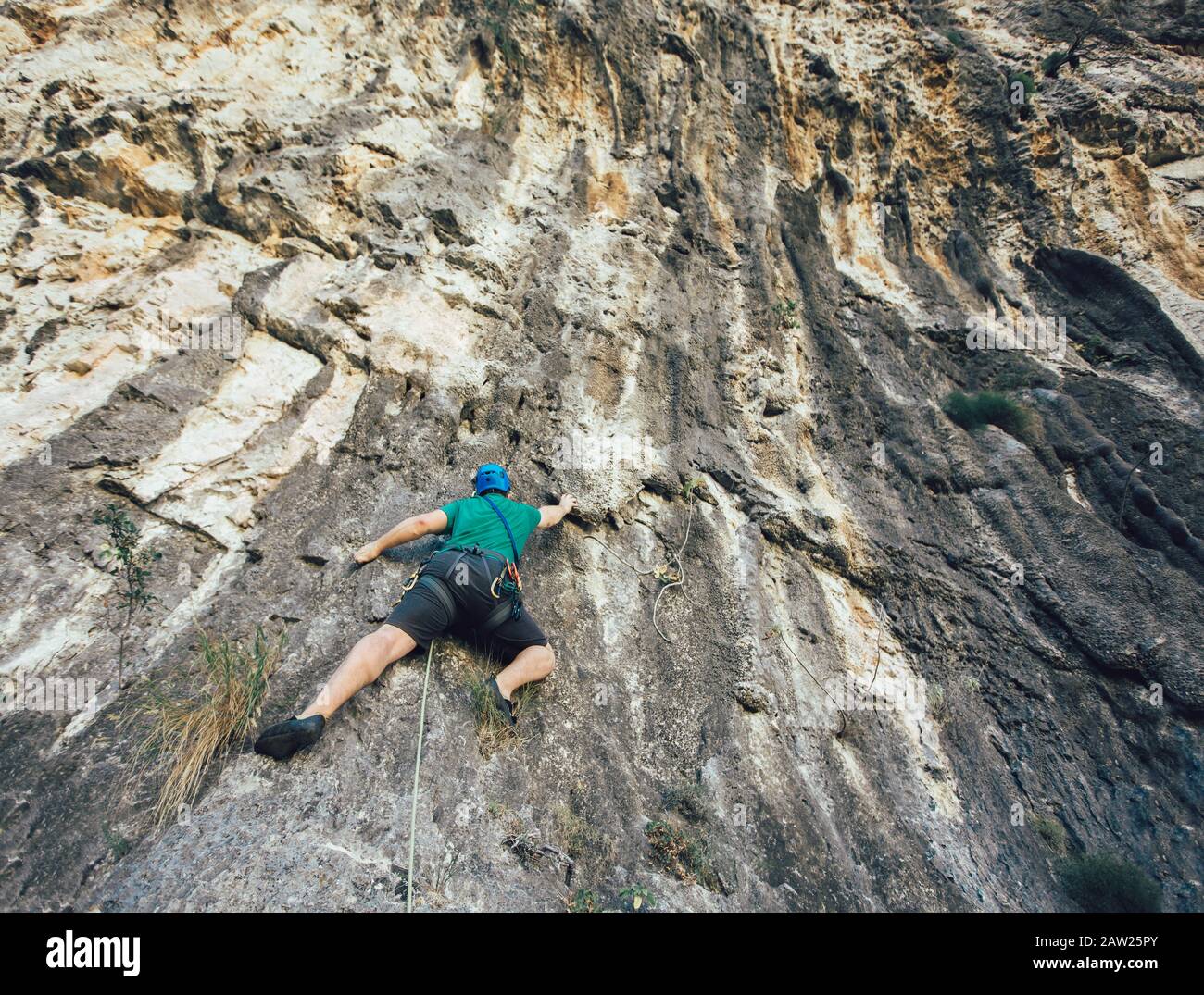 Man with a rope engaged in the sports of rock climbing on the rock ...