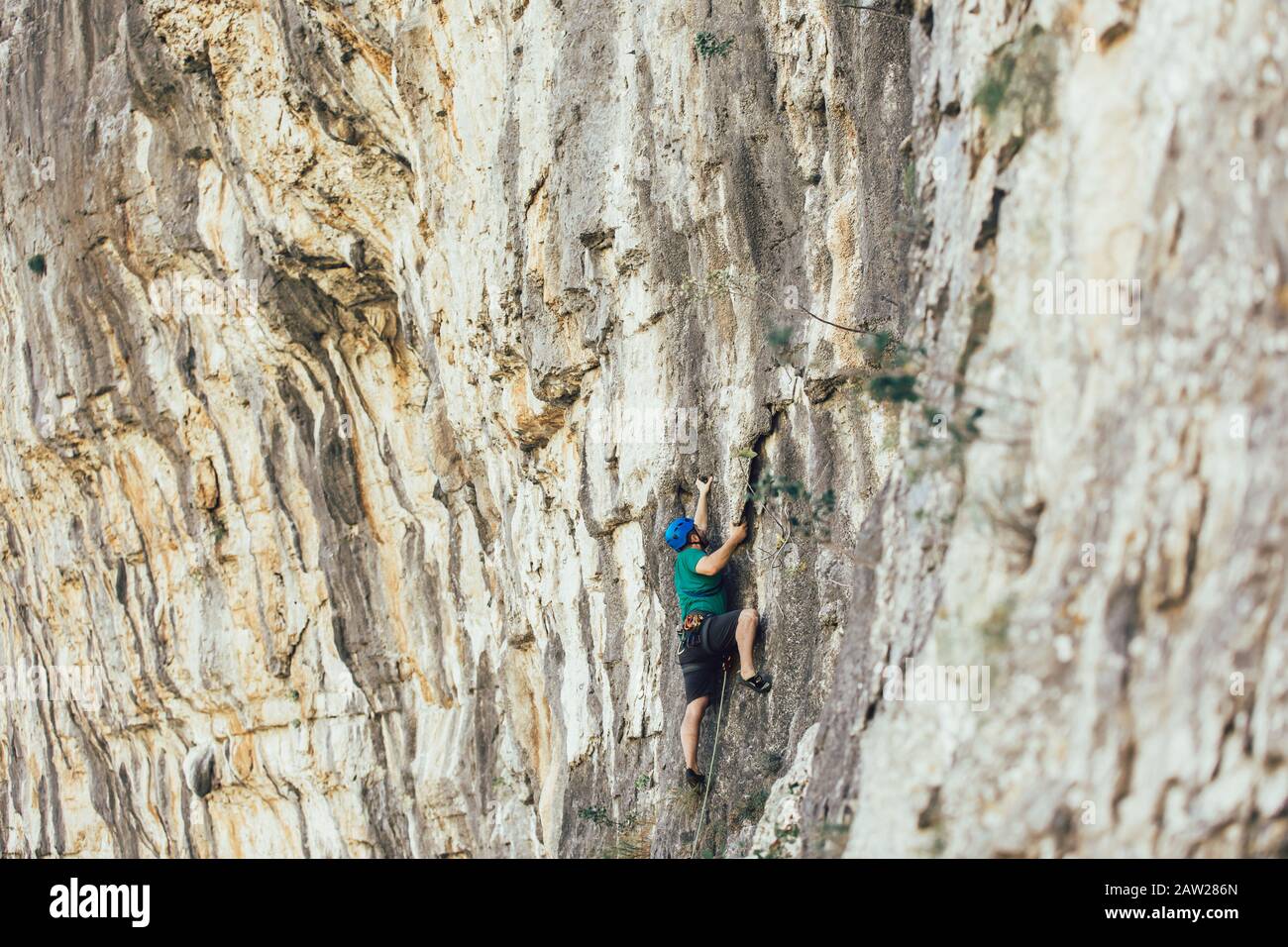 Man with a rope engaged in the sports of rock climbing on the rock ...