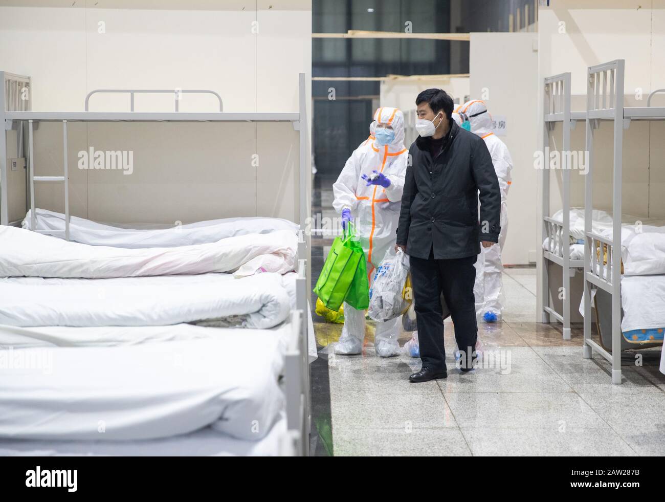 Chinese medical workers escort a patient infected with the new ...