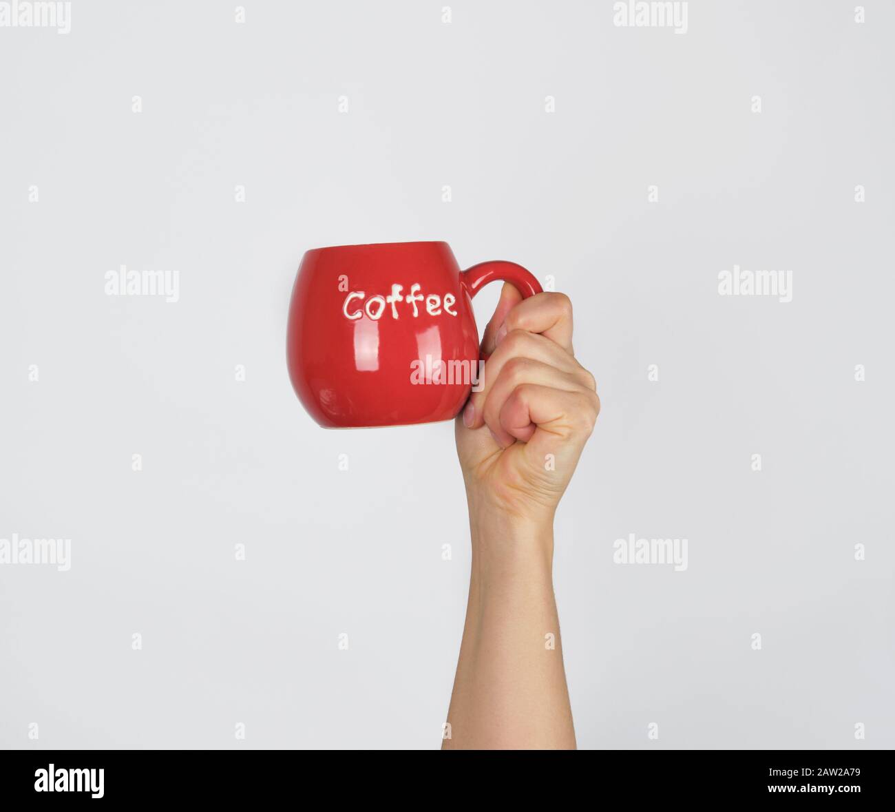 red ceramic cup in a female hand on a white background, hand is raised ...