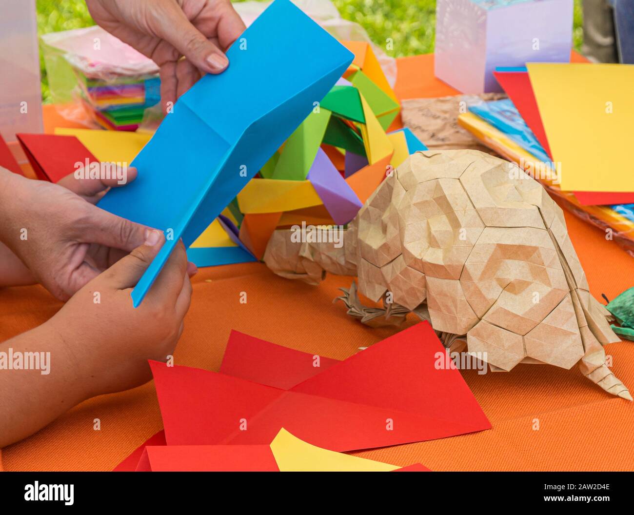 Children's hands do origami from colored paper on white background ...