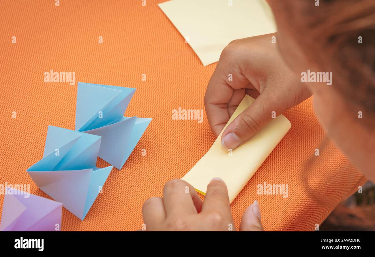 Children's hands do origami from colored paper on white background ...