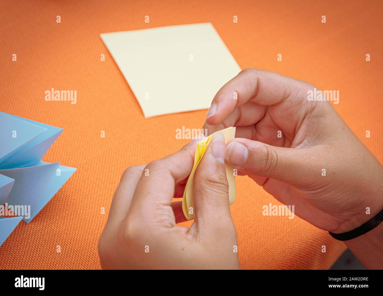Children's hands do origami from colored paper on white background ...