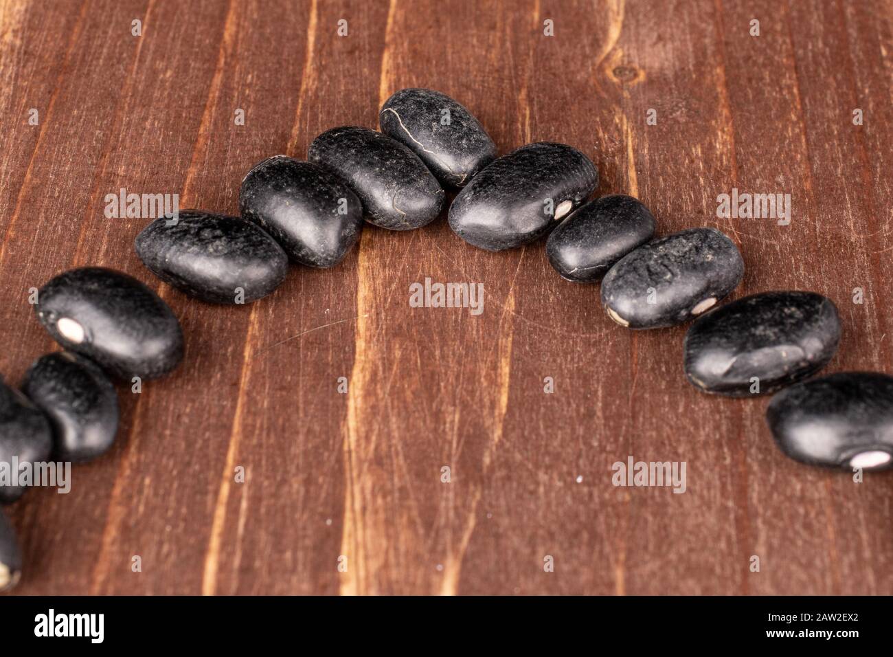 Lot of whole small black bean on brown wood Stock Photo - Alamy