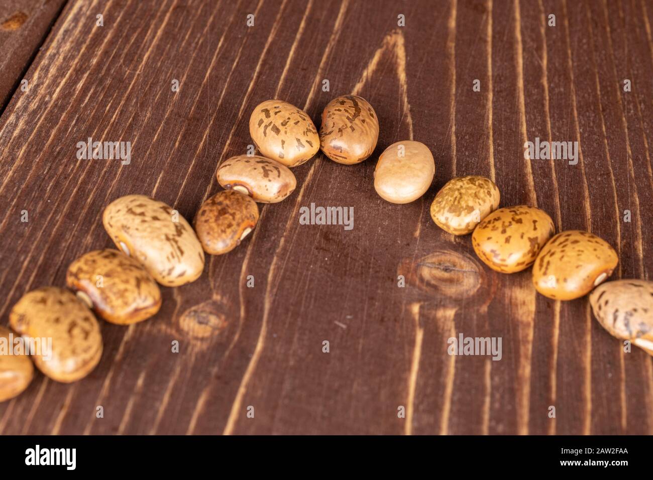 Group of thirteen whole mottled brown bean pinto on brown wood Stock ...