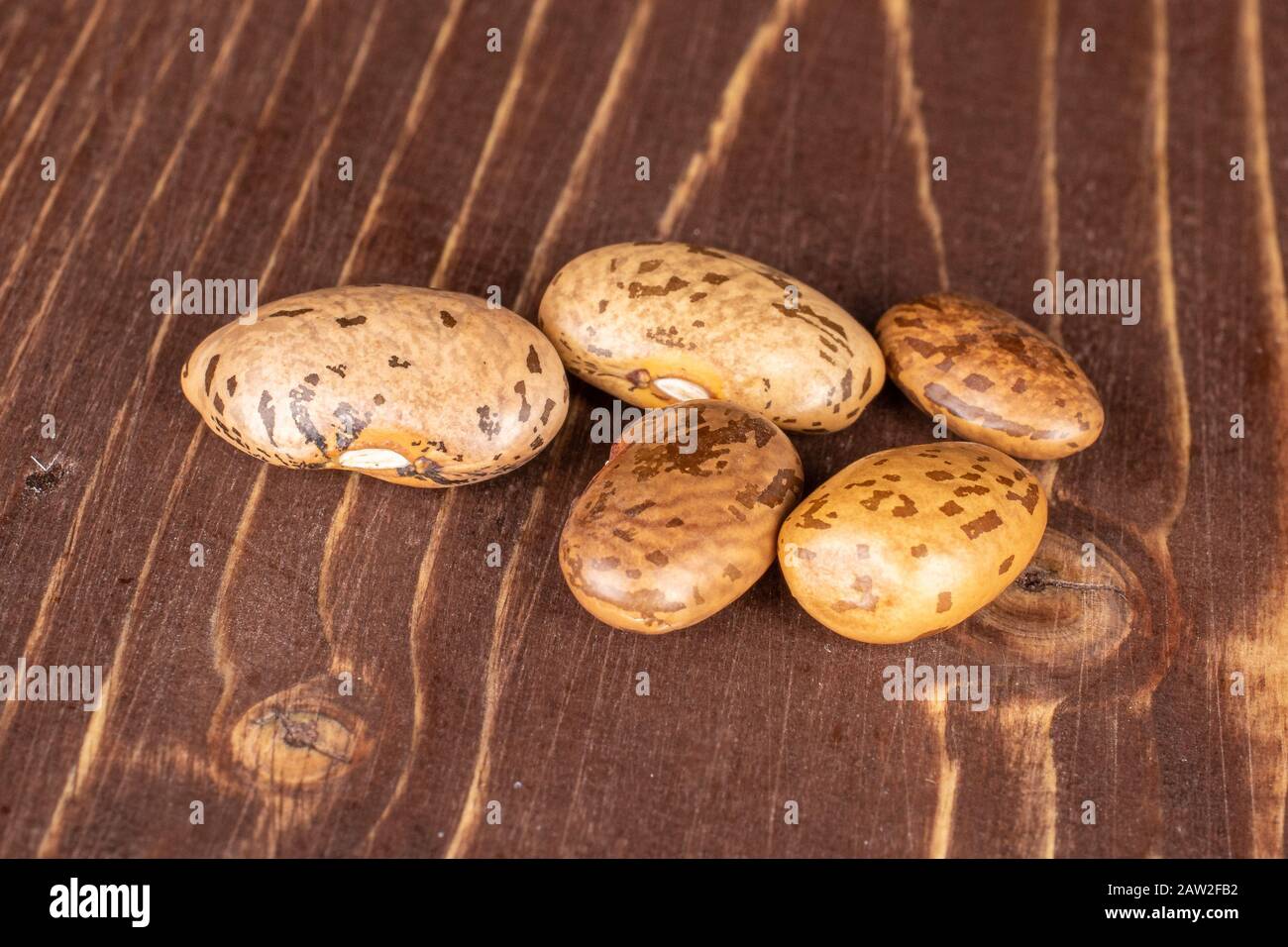 Group of five whole mottled brown bean pinto on brown wood Stock Photo ...