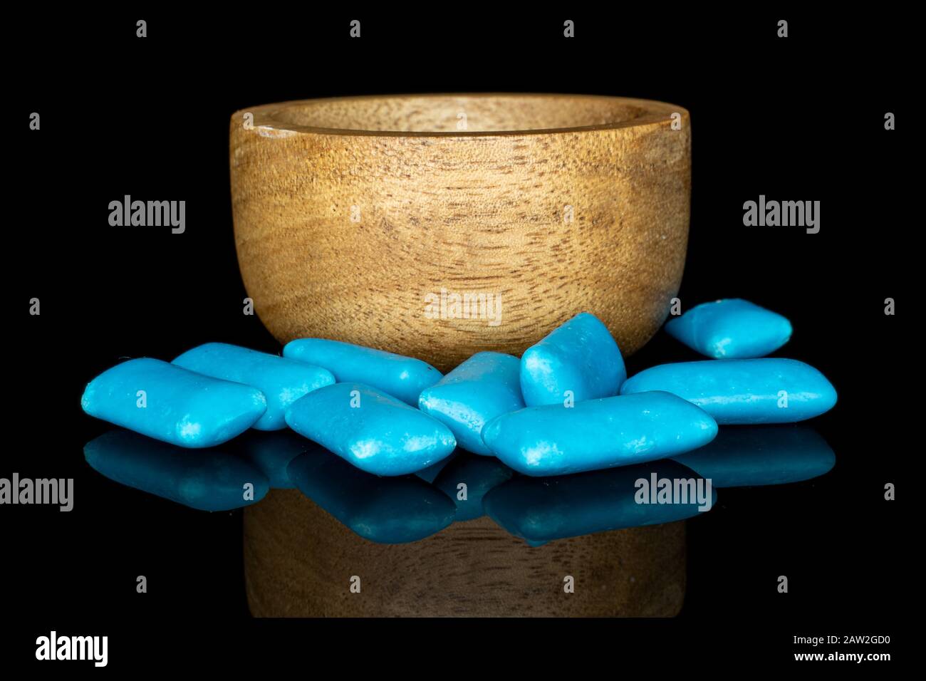 Group of nine whole blue chewing gum in bamboo bowl isolated on black ...