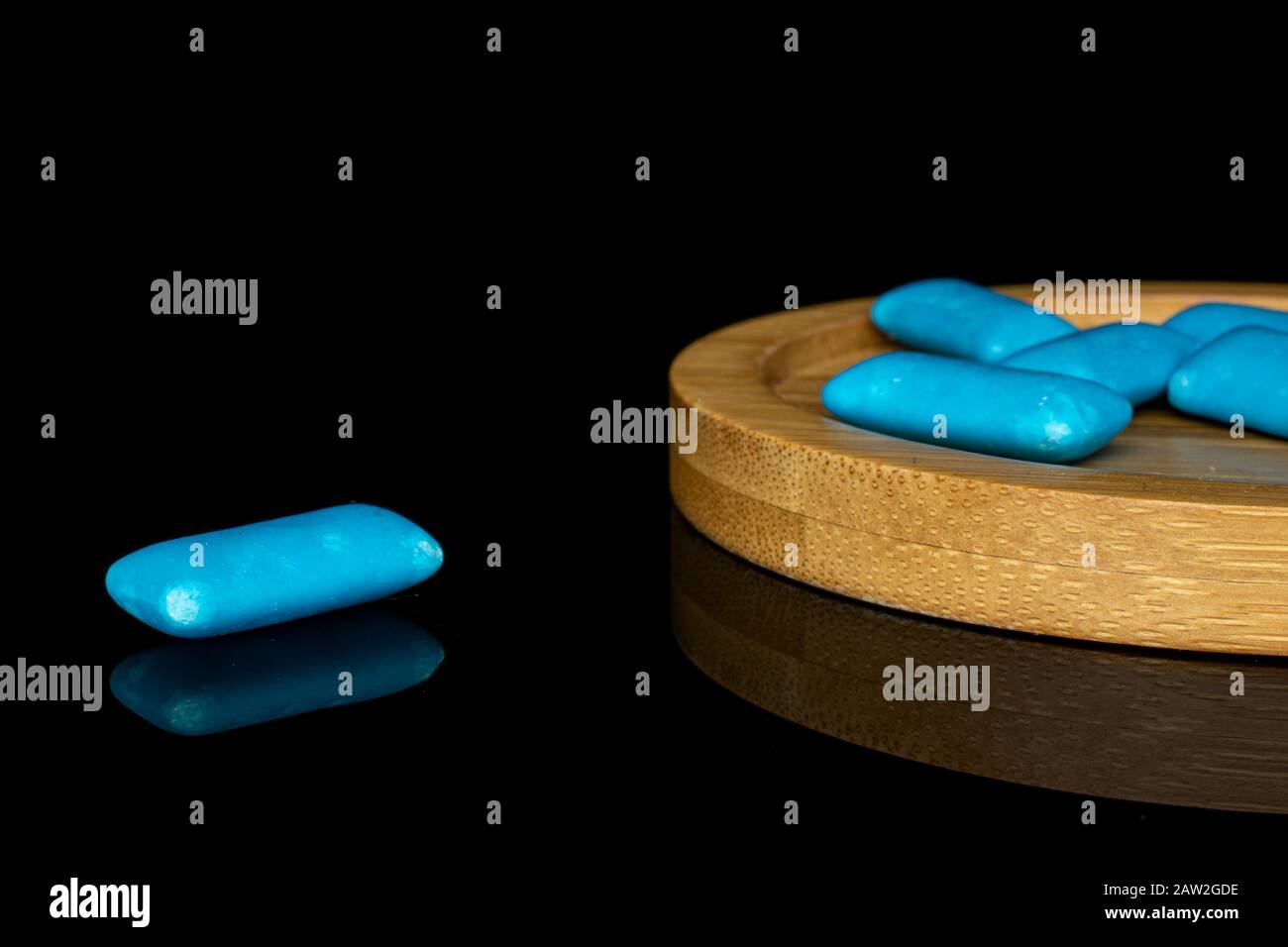 Group of six whole blue chewing gum on round bamboo coaster isolated on ...