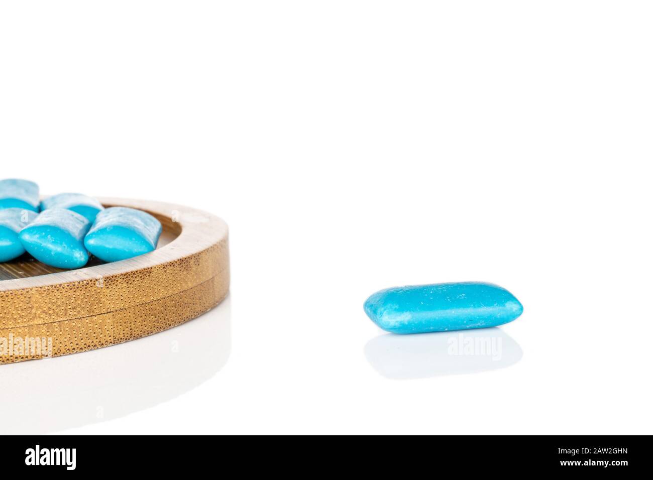 Group of six whole blue chewing gum on round bamboo coaster isolated on ...