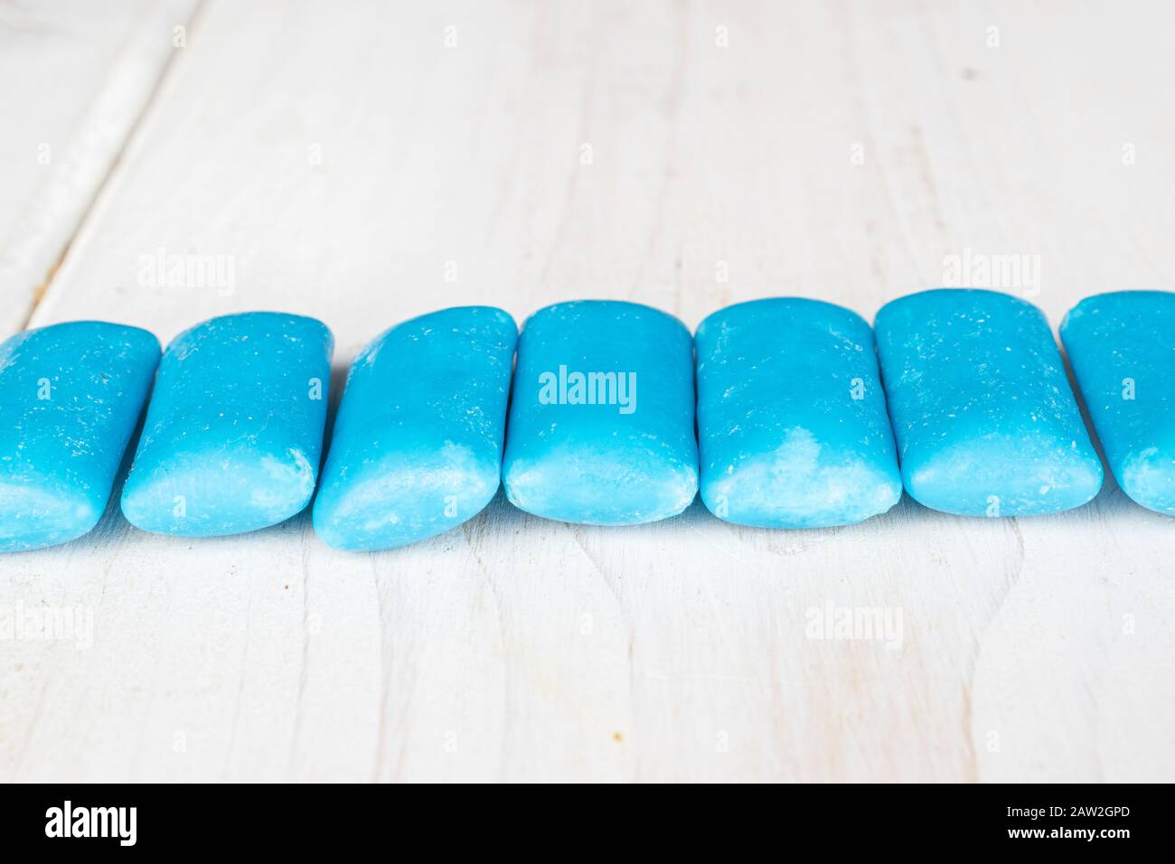 Group of seven whole blue chewing gum on white wood Stock Photo - Alamy