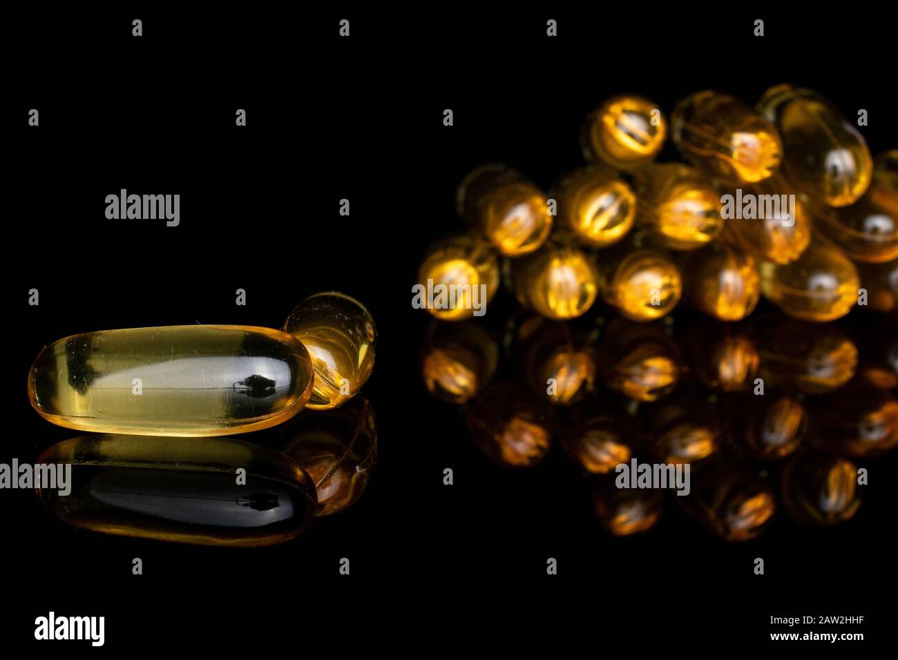 Lot of whole arranged golden fish oil isolated on black glass Stock ...