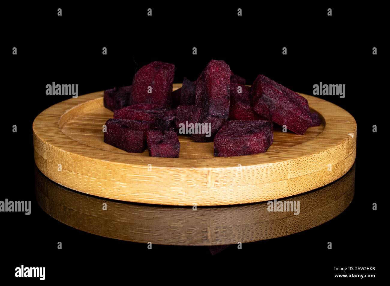 Lot of pieces of raw sweet beetroot on round bamboo coaster isolated on ...