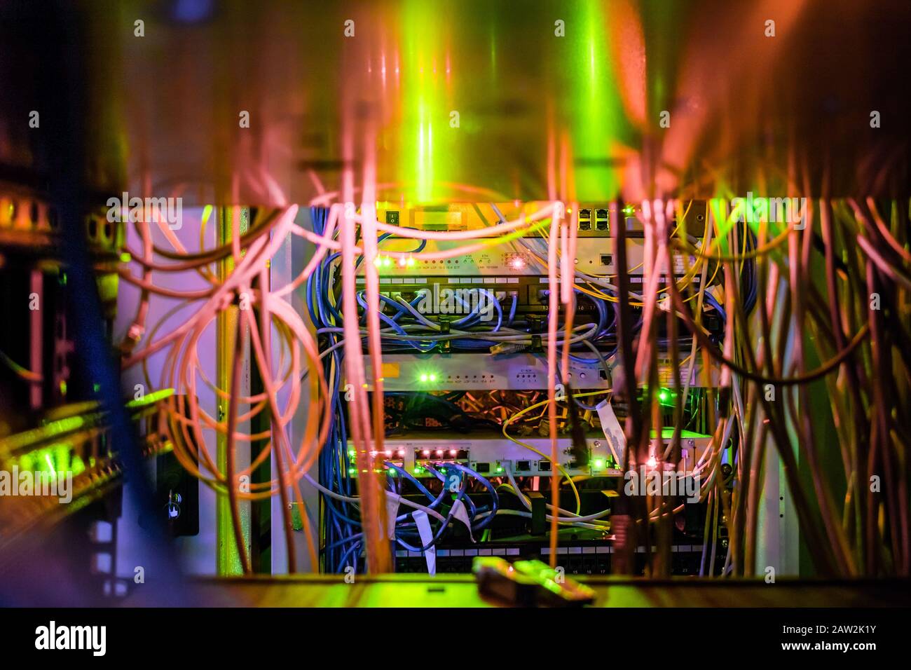 Many wires are stacked between servers in a dark room of the data ...